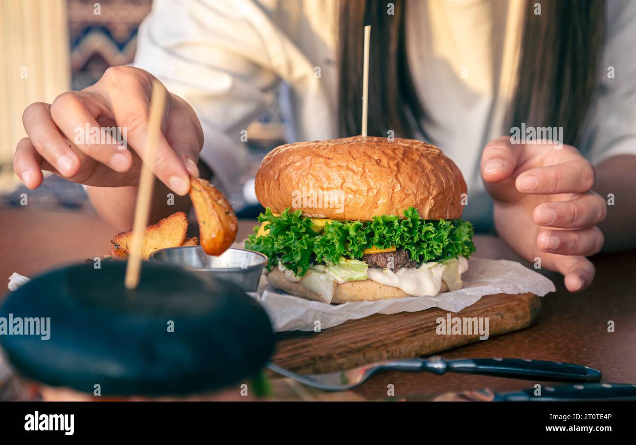 A young woman eating burger in street cafe, close up Stock Photo - Alamy