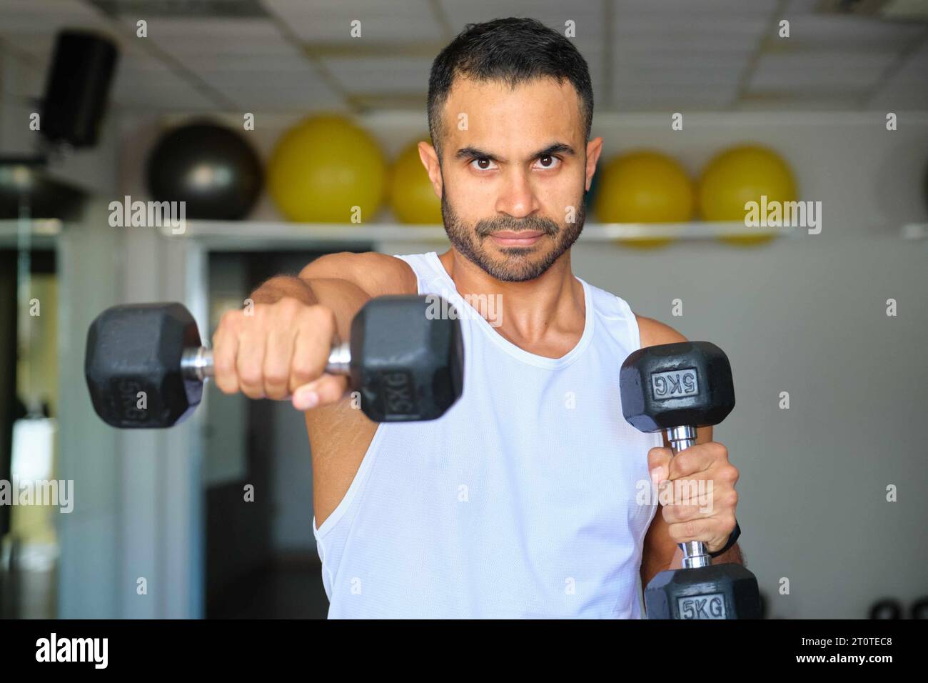 Strong Hispanic man training boxing with weights at a gym Stock Photo ...