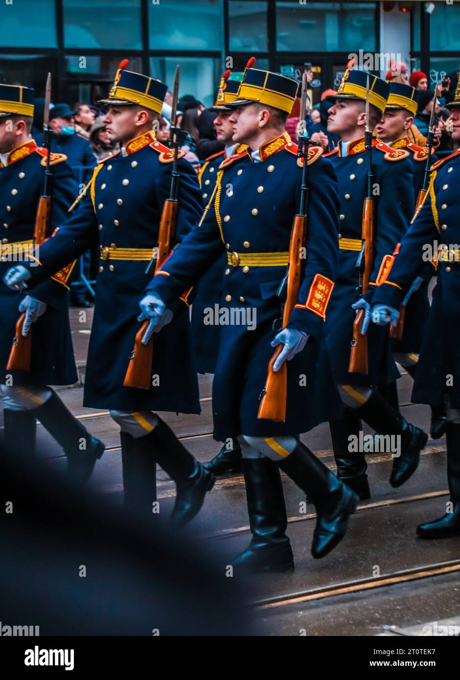 A group of soldiers in matching uniforms march in unison down a city ...