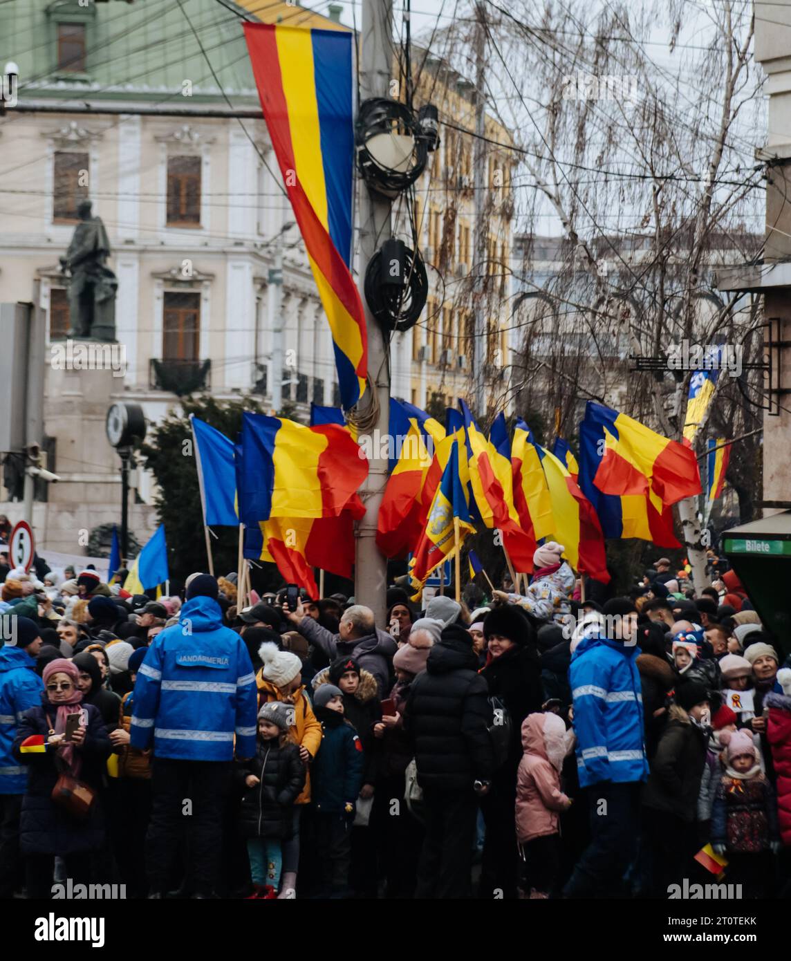 A diverse crowd of people with flags in hand assembled on a street ...