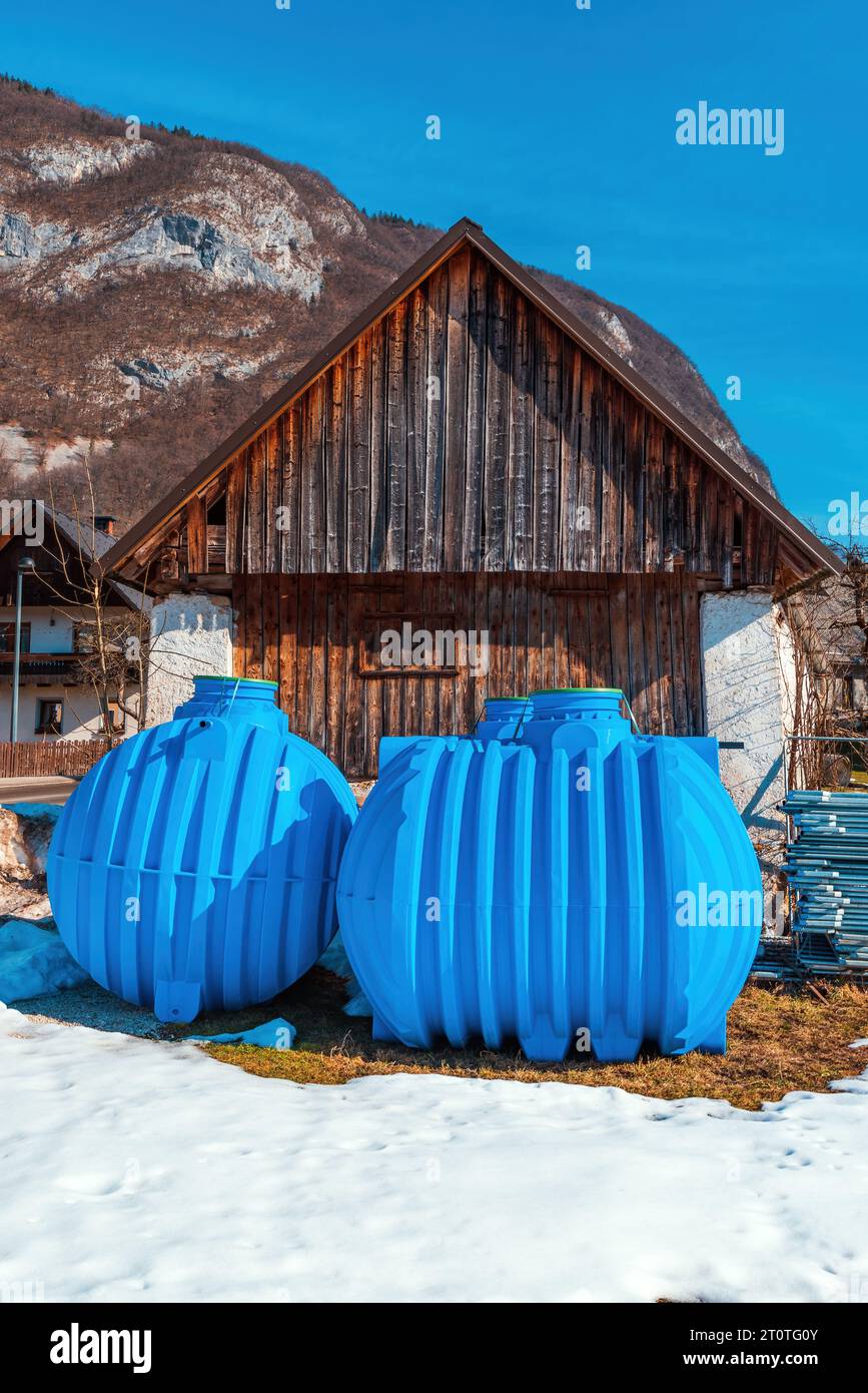 Two blue rainwater tanks in front of wooden shed in Slovenia, selective ...