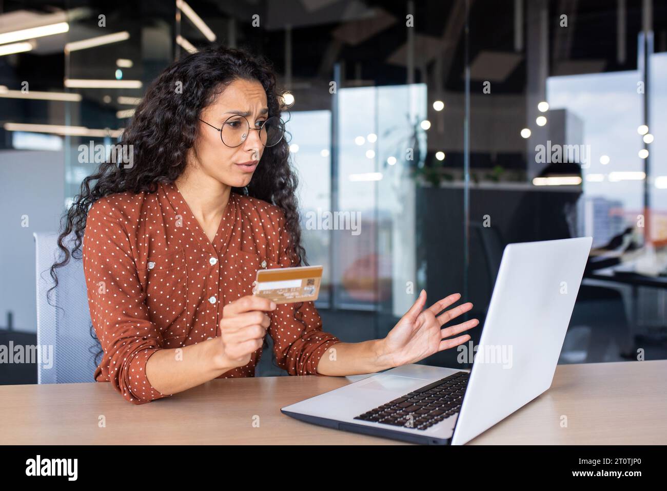 Upset and shocked business woman with bank credit card and laptop ...