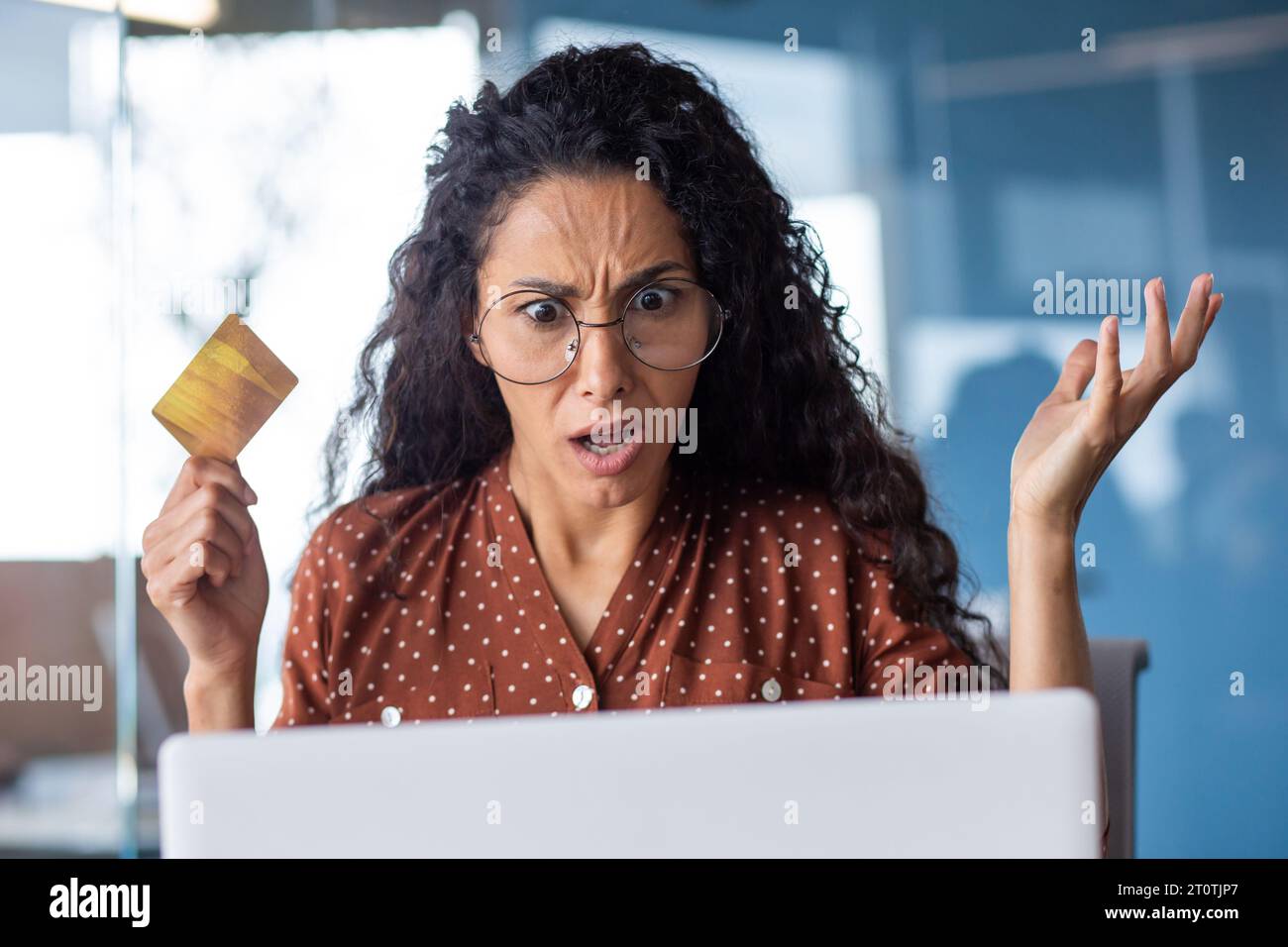 Upset and shocked business woman with bank credit card and laptop ...