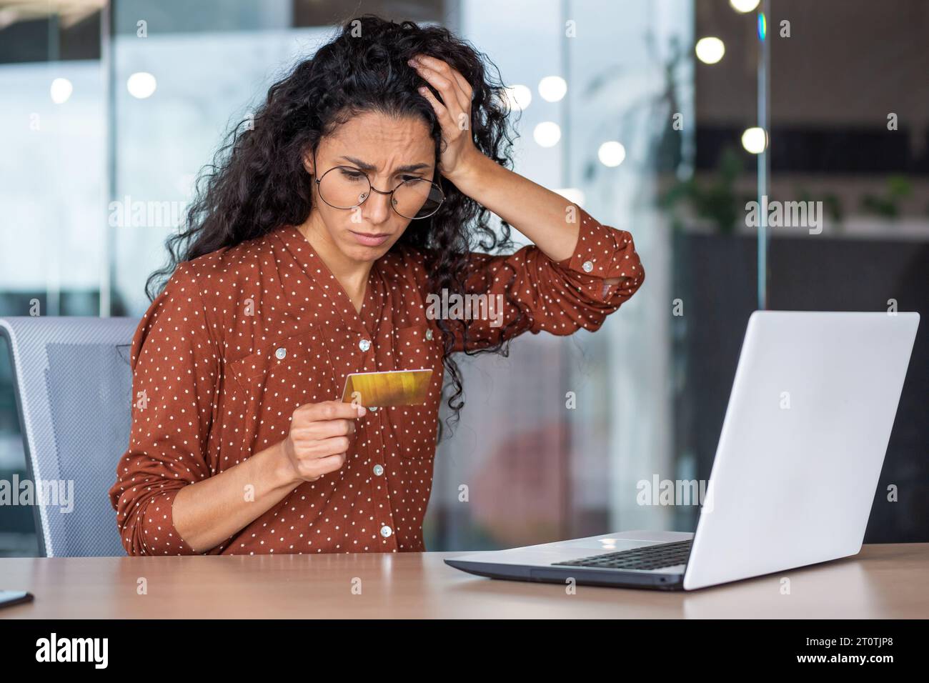 Upset and shocked business woman with bank credit card and laptop ...