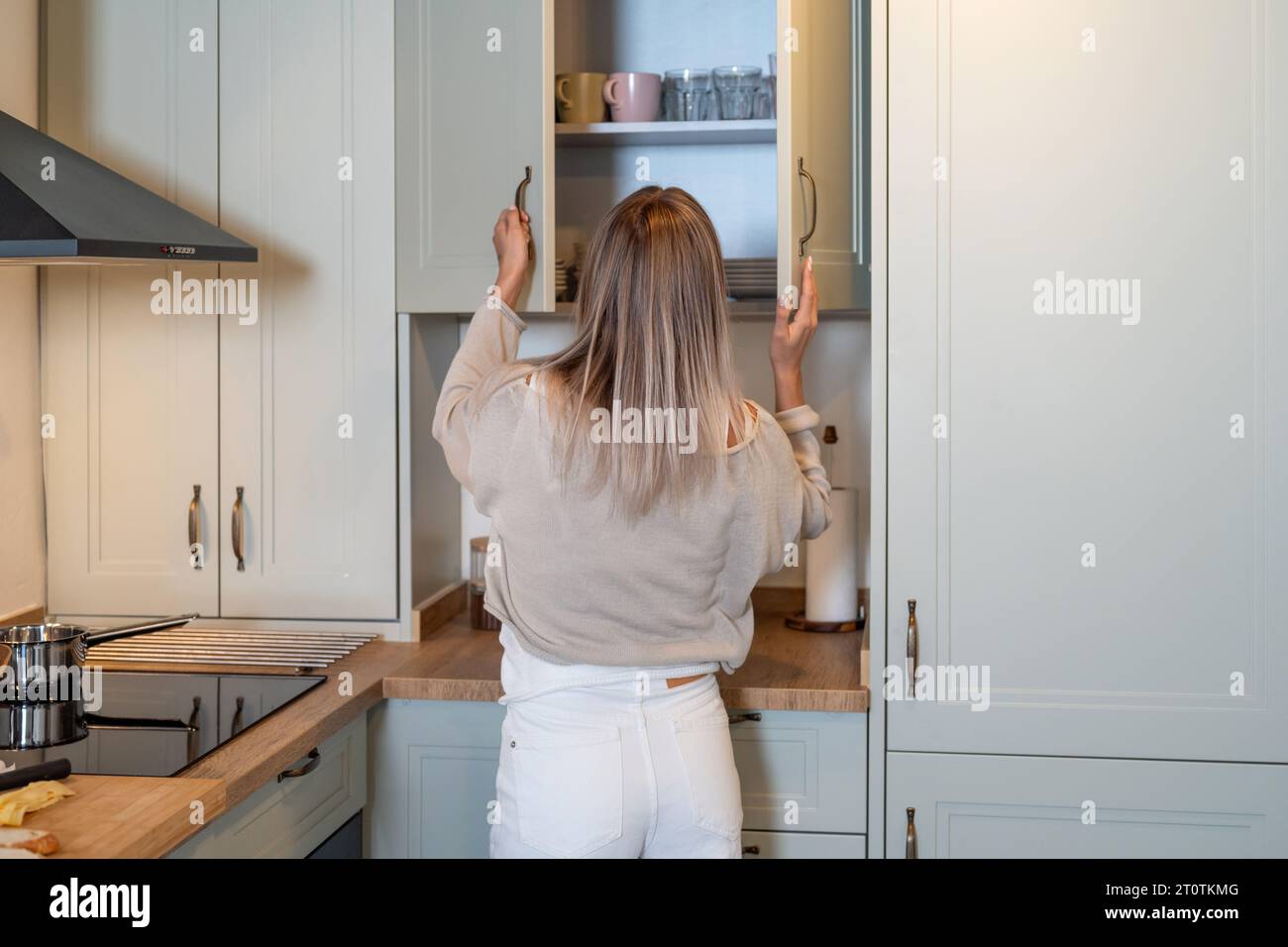 Back view of Caucasian woman in casual outfit standing at cupboard in ...
