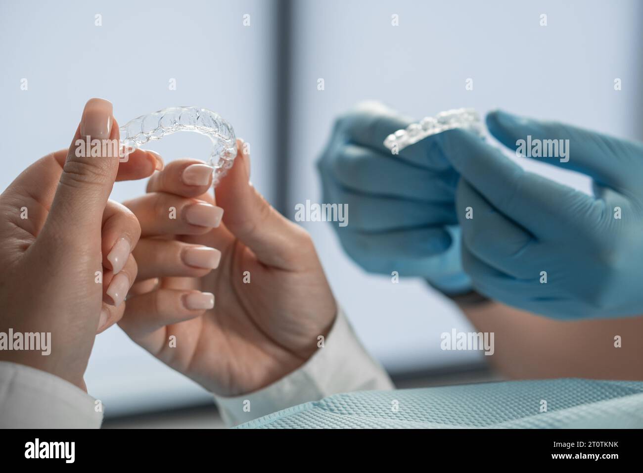 The hands of the doctor and the patient hold the veneers close-up. The ...