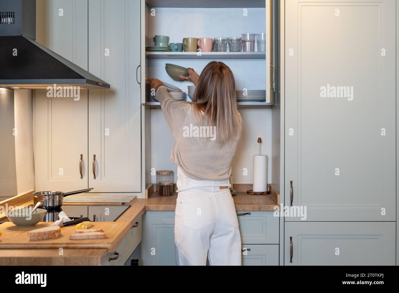 Back view of Caucasian woman in casual outfit standing at cupboard in ...