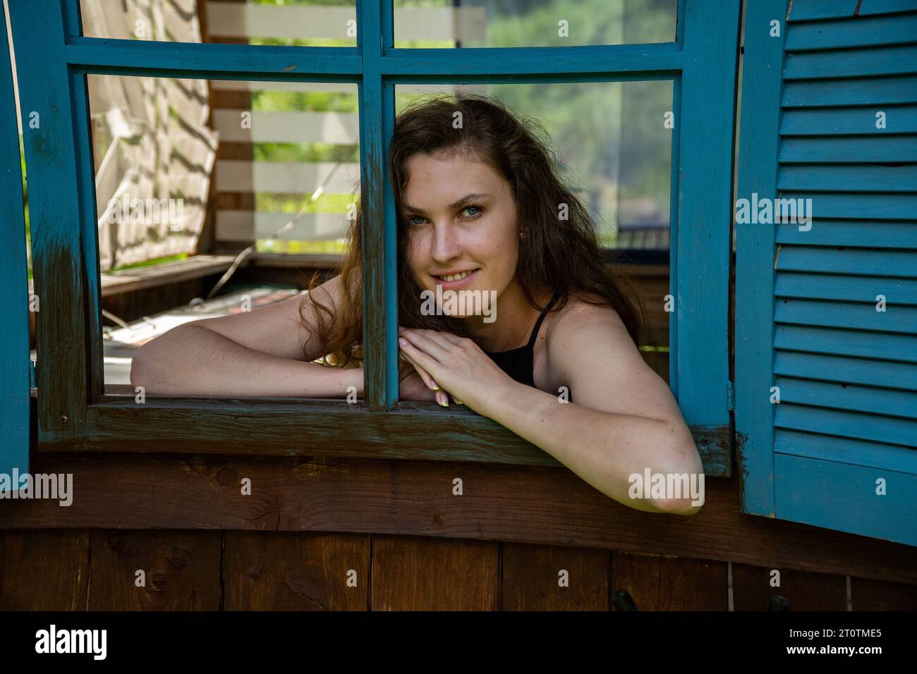 Shot of sad young woman crying while looking through the window at home ...