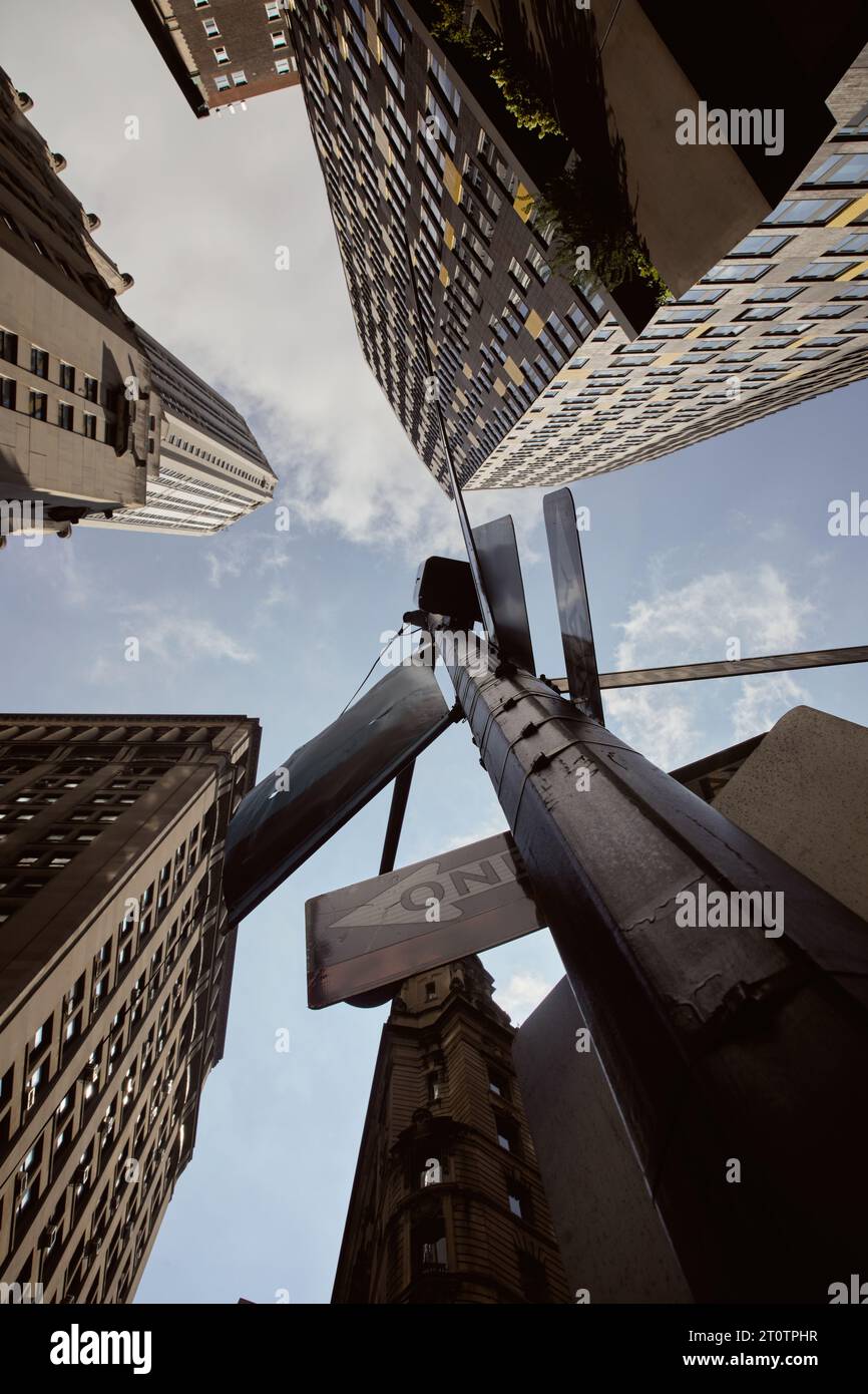 bottom view of street pole with traffic signs near tall buildings ...