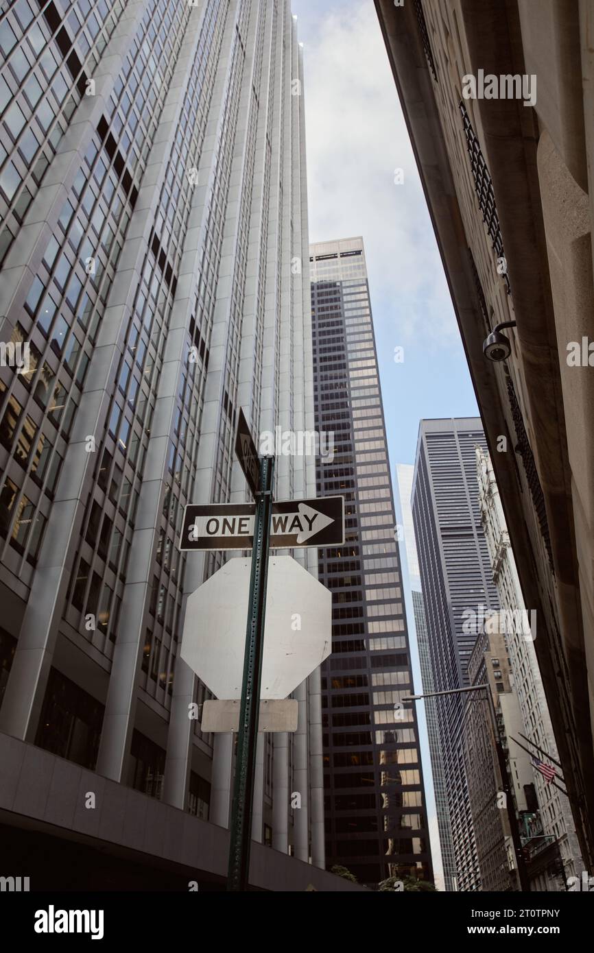 low angle view of one way road sign near modern buildings and ...