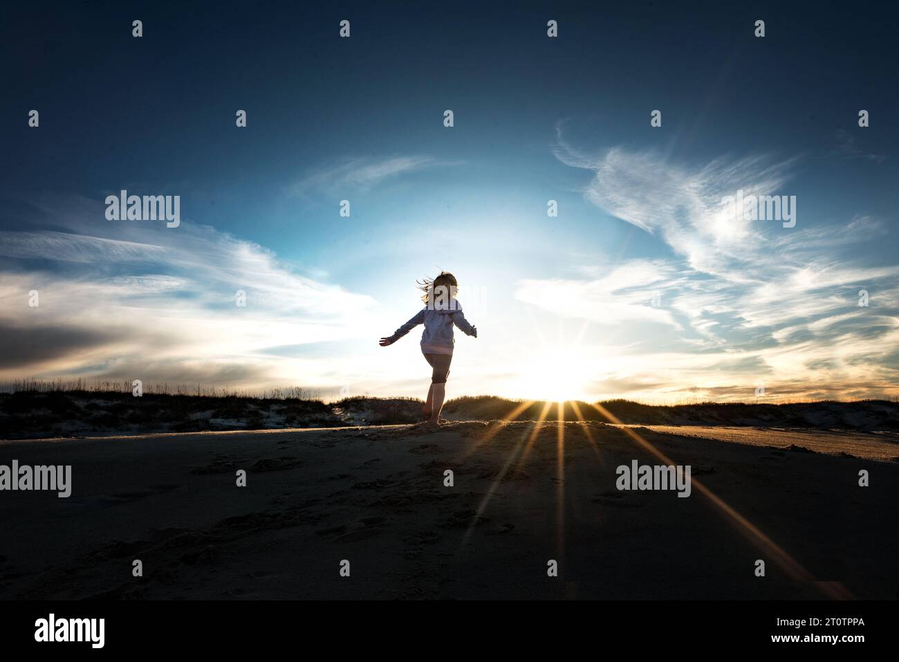 Young girl running towards the sunset under big blue sky Stock Photo ...