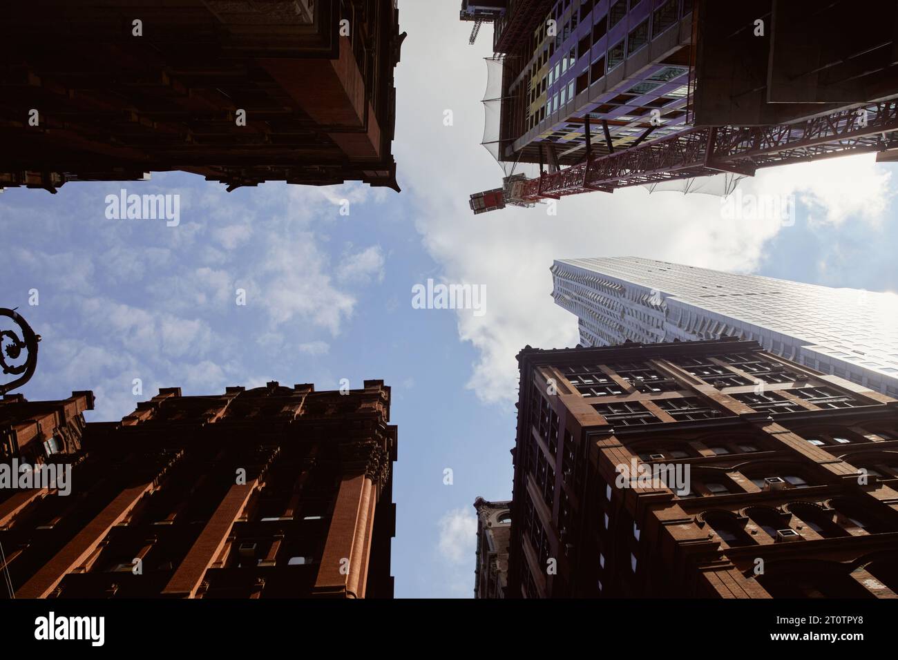 bottom view of modern and vintage buildings against blue cloudy sky in ...