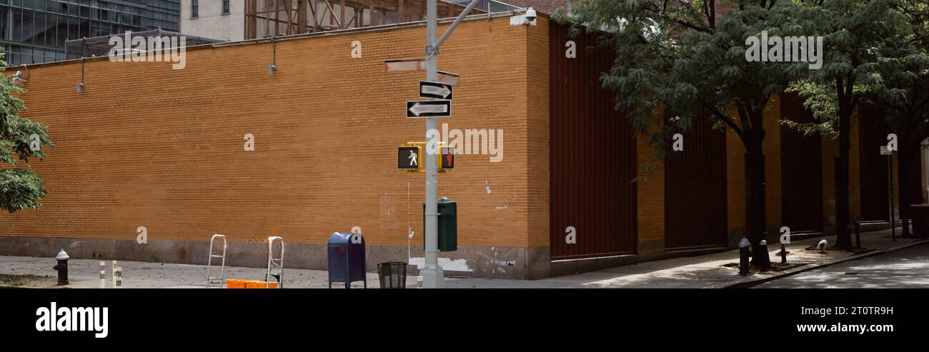 brick fence near trees and road pole with traffic signs on roadway in ...