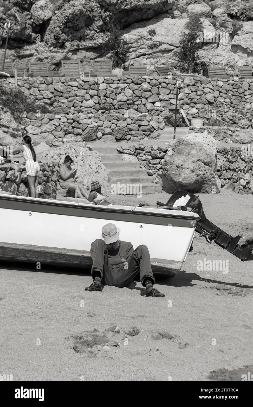 Elderly man with hat leaning on a boat while sleeping on the St Paul's ...
