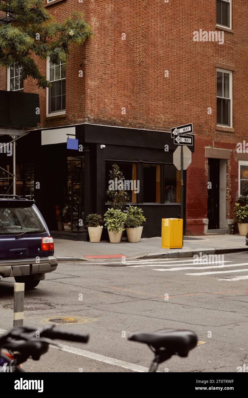 brick building with storefront and flowerpots near crossroad in new ...