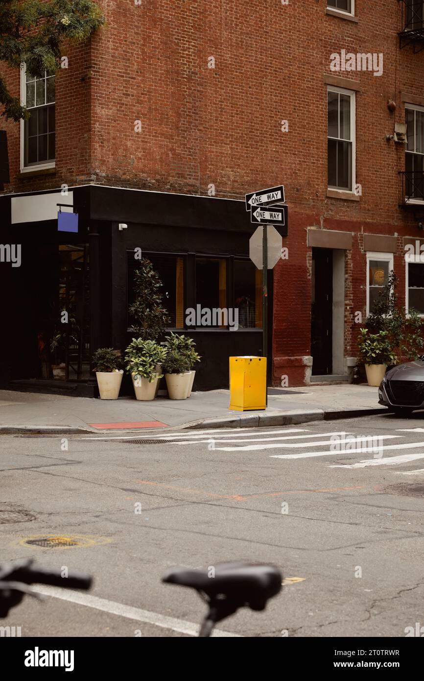 brick building with storefront and flowerpots near crossroad in new ...