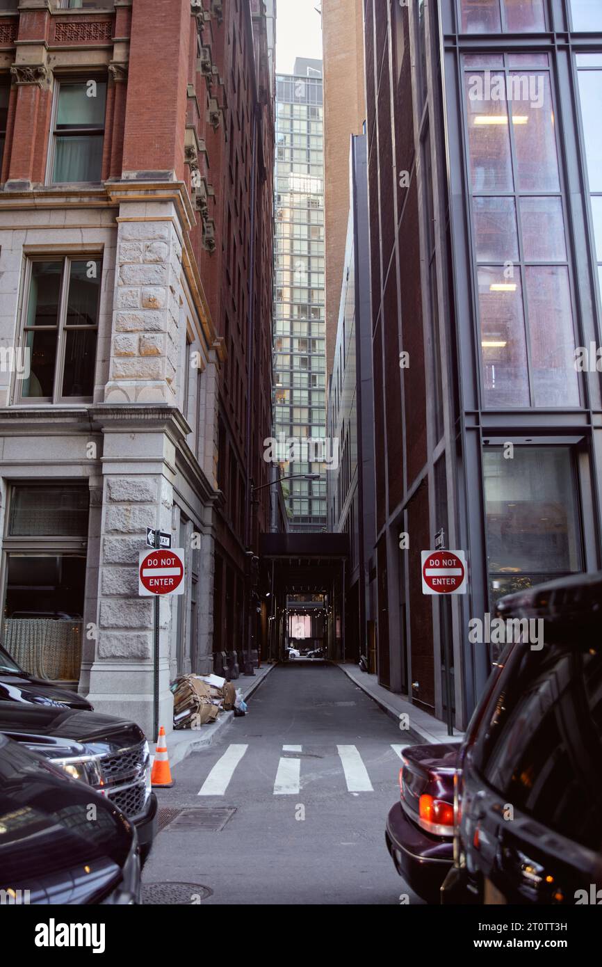 cars parked near do not enter road signs between modern buildings on ...