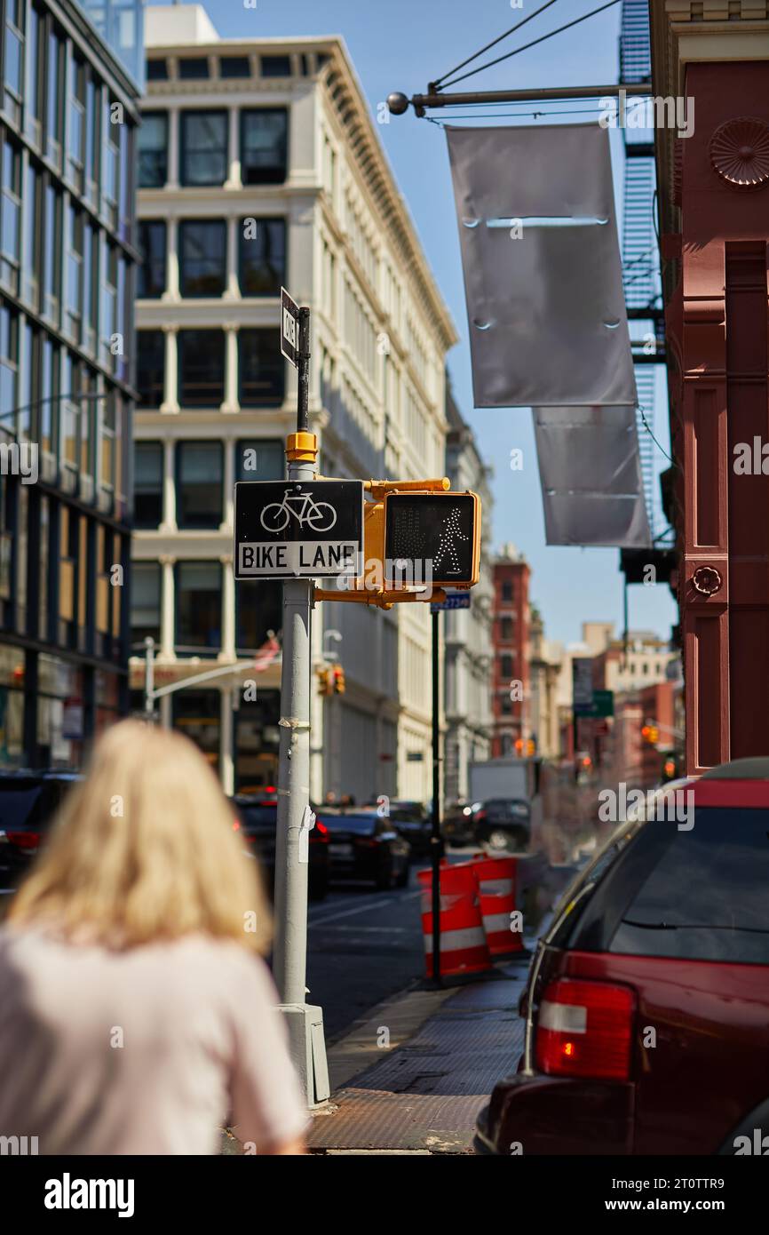 back view of blurred pedestrian on street with bike lane sign and ...
