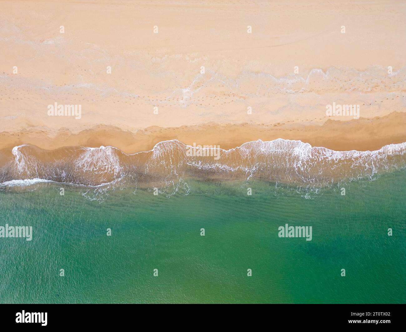 A top-down aerial view of a sandy beach and sea is a breathtaking sight ...