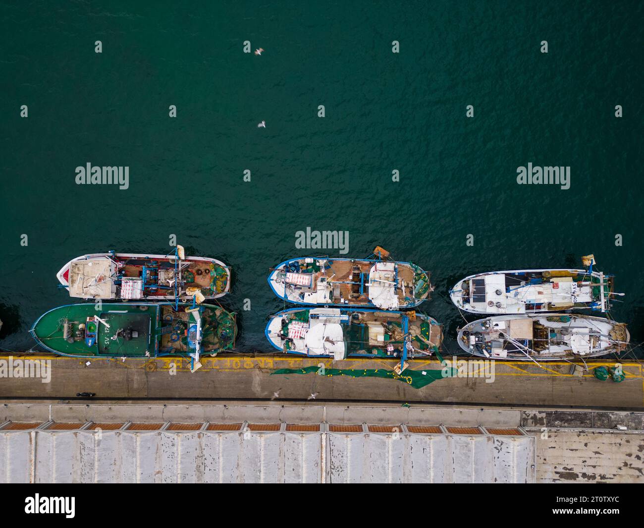 An aerial top view of fishing boats in the port reveals the vibrant ...