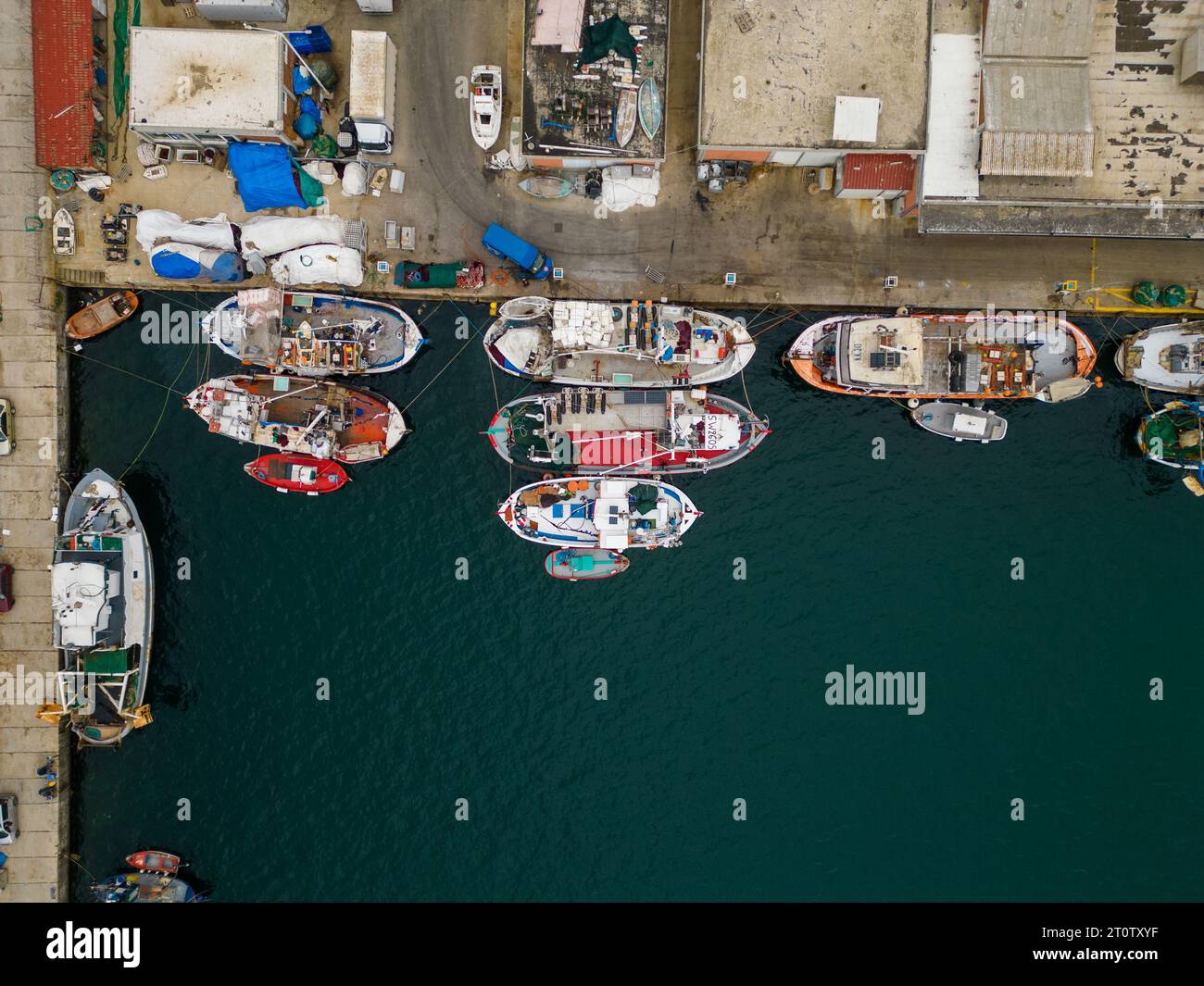 An aerial top view of fishing boats in the port reveals the vibrant ...