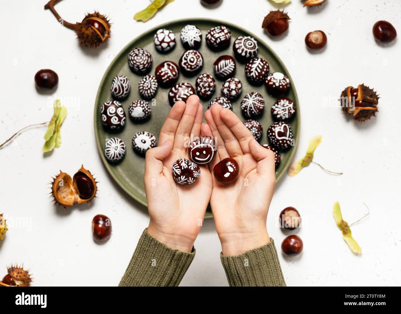 Beautiful hand painted chestnuts with different motifs hold by hands ...