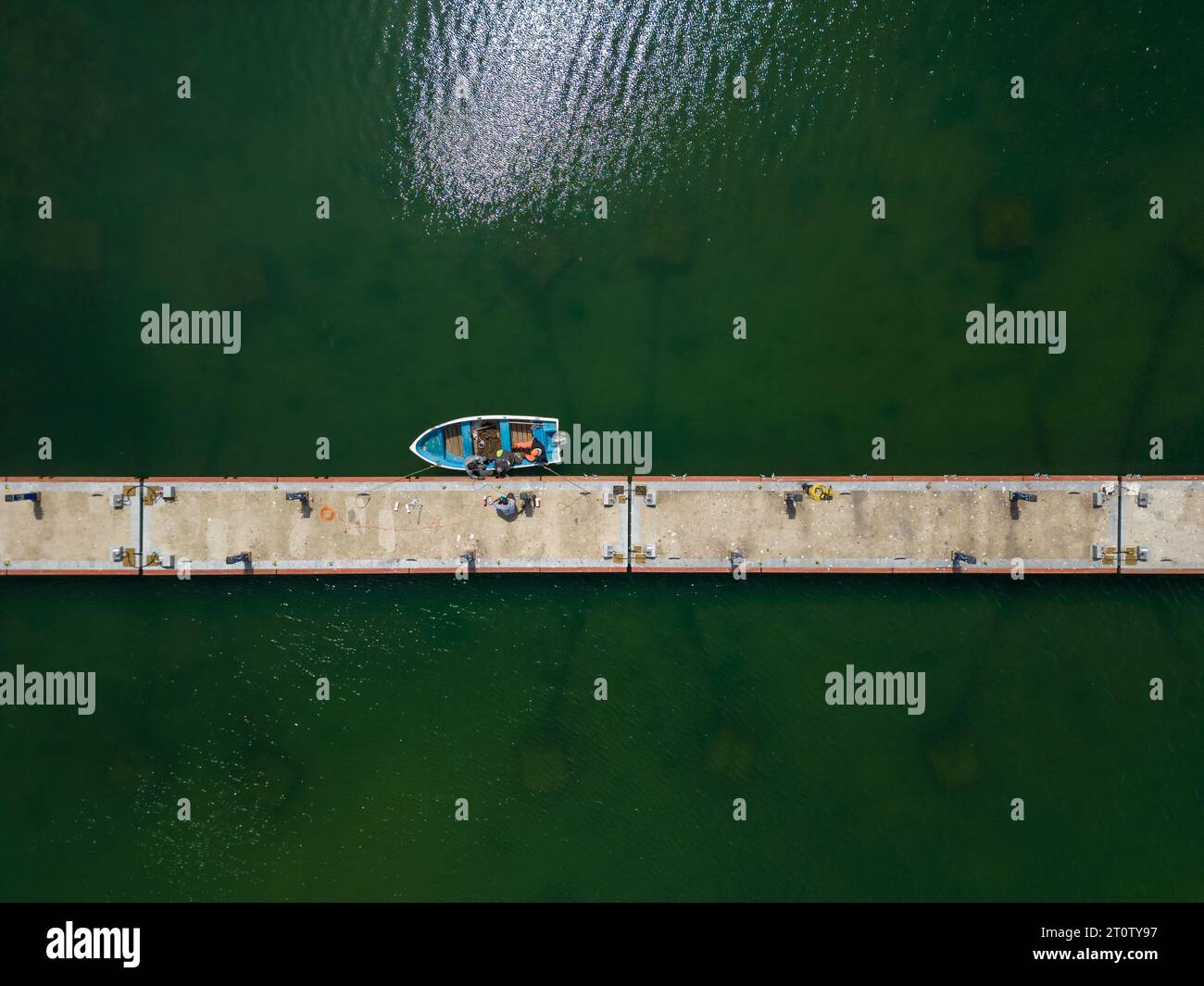 aerial top down view of a serene dock in the sea, with several fishing ...