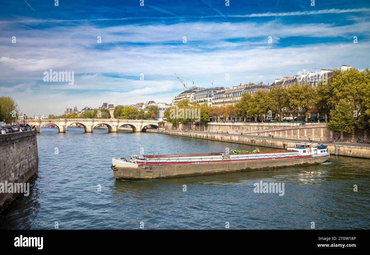 A motorised barge turns on the River Seine next to Pont d'Arcole ...