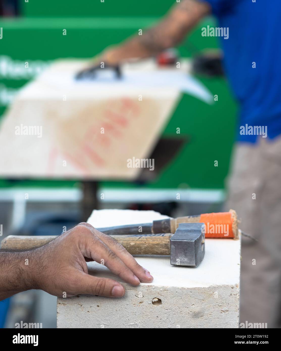 A French stonemason rests his hand next to a hammer and chisel while ...