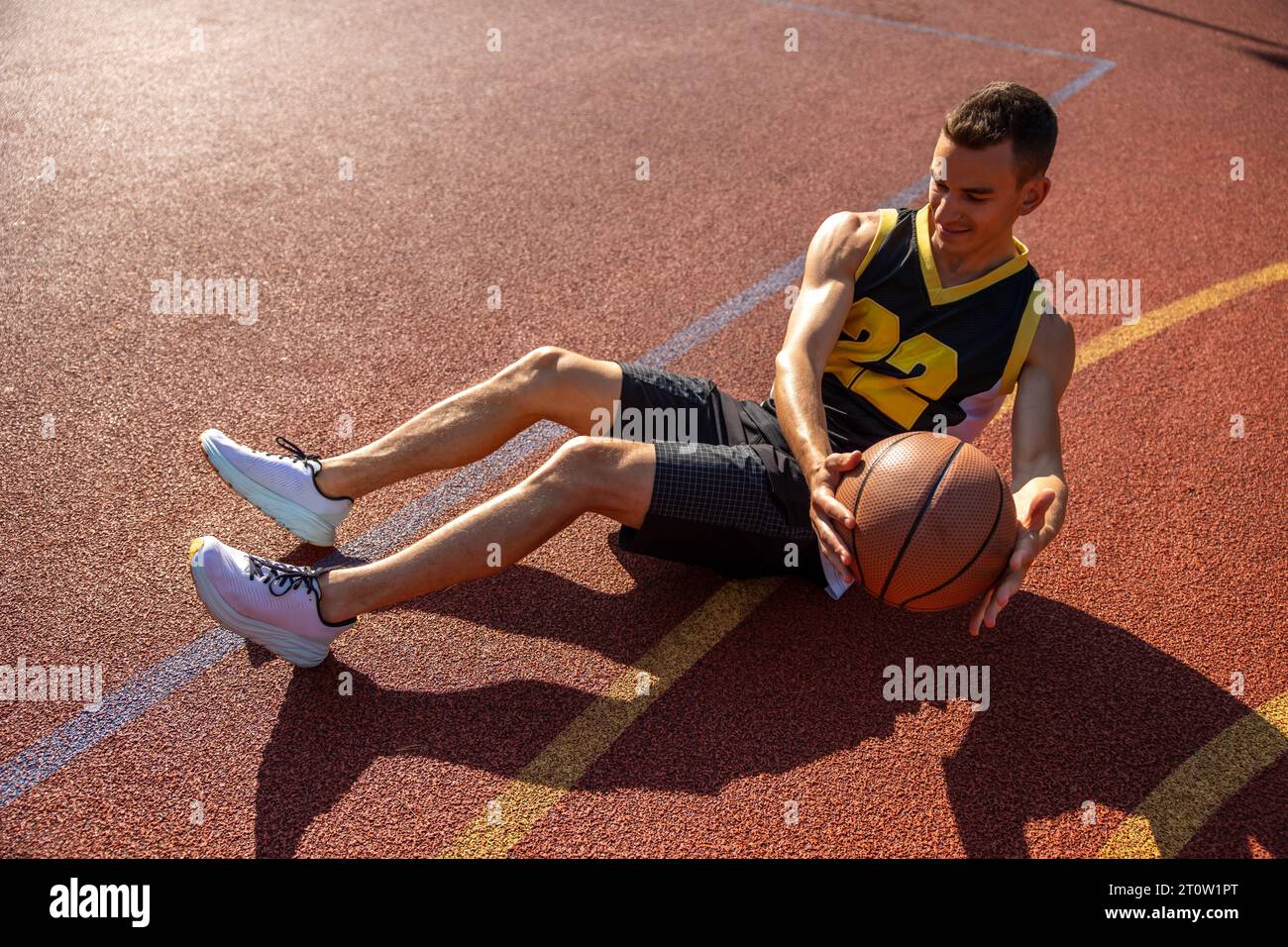 Sporty man doing abs workout with ball outdoor on basketball court ...