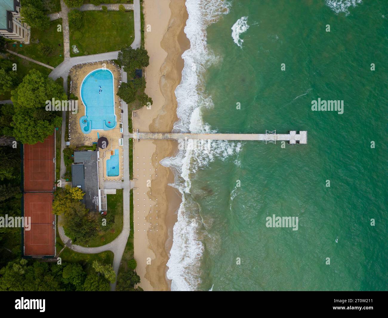 Aerial top view of a long pier extending into the sea, located at a ...
