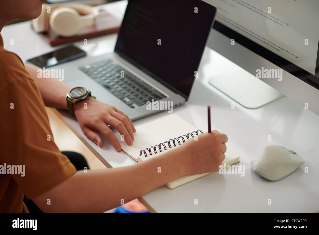 Software developer writing plans for the day in planner before starting ...