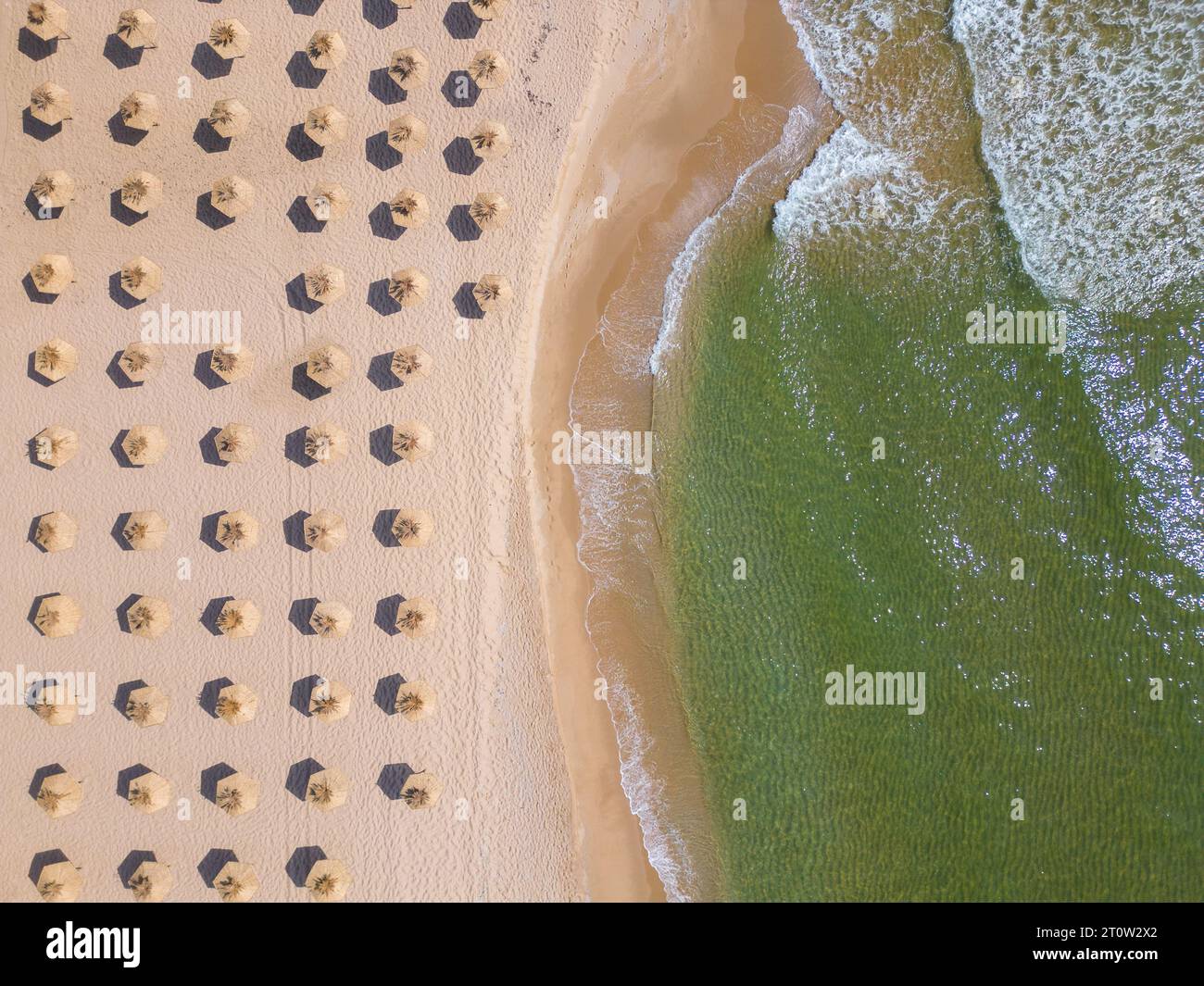Aerial top view of an amazing empty sand beach with straw beach ...