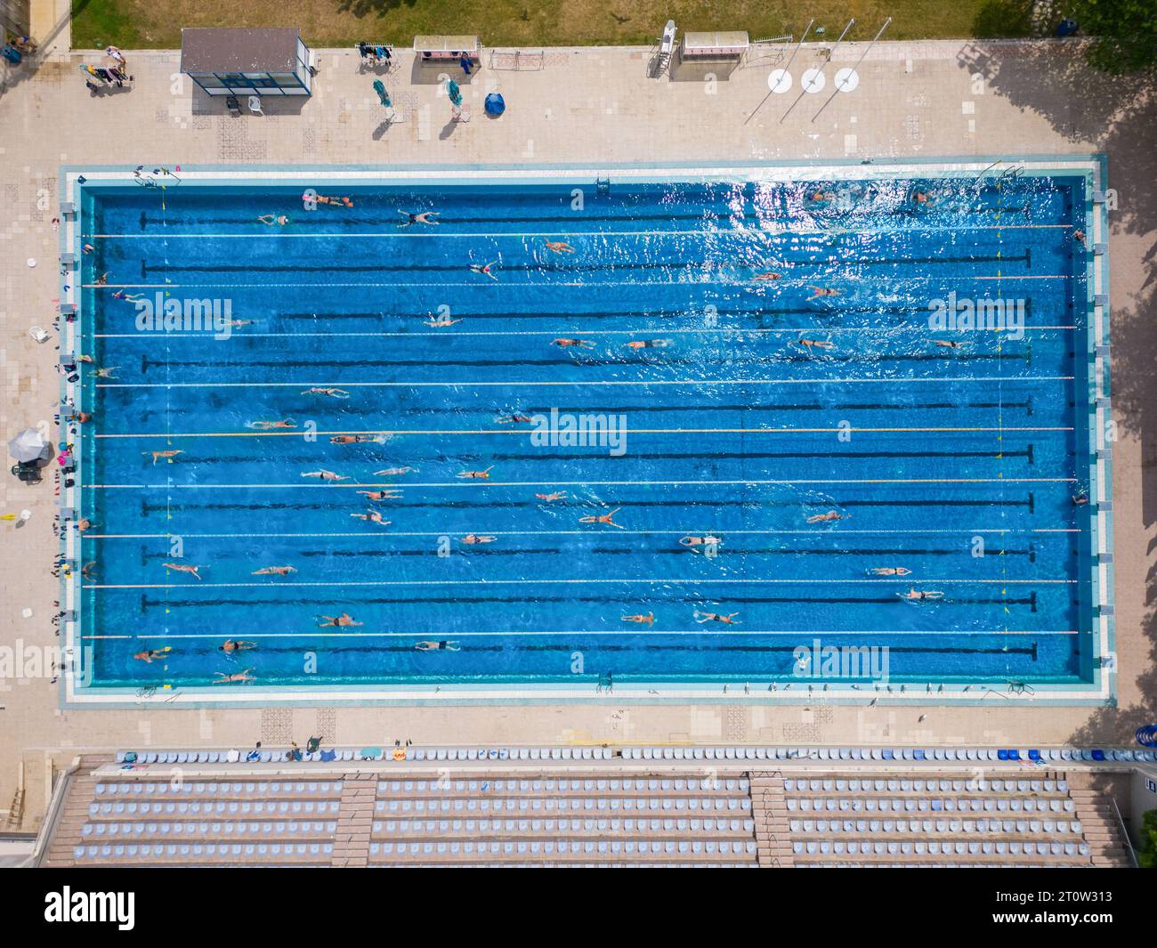 The open sports swimming pool glistened under the bright sun as people ...