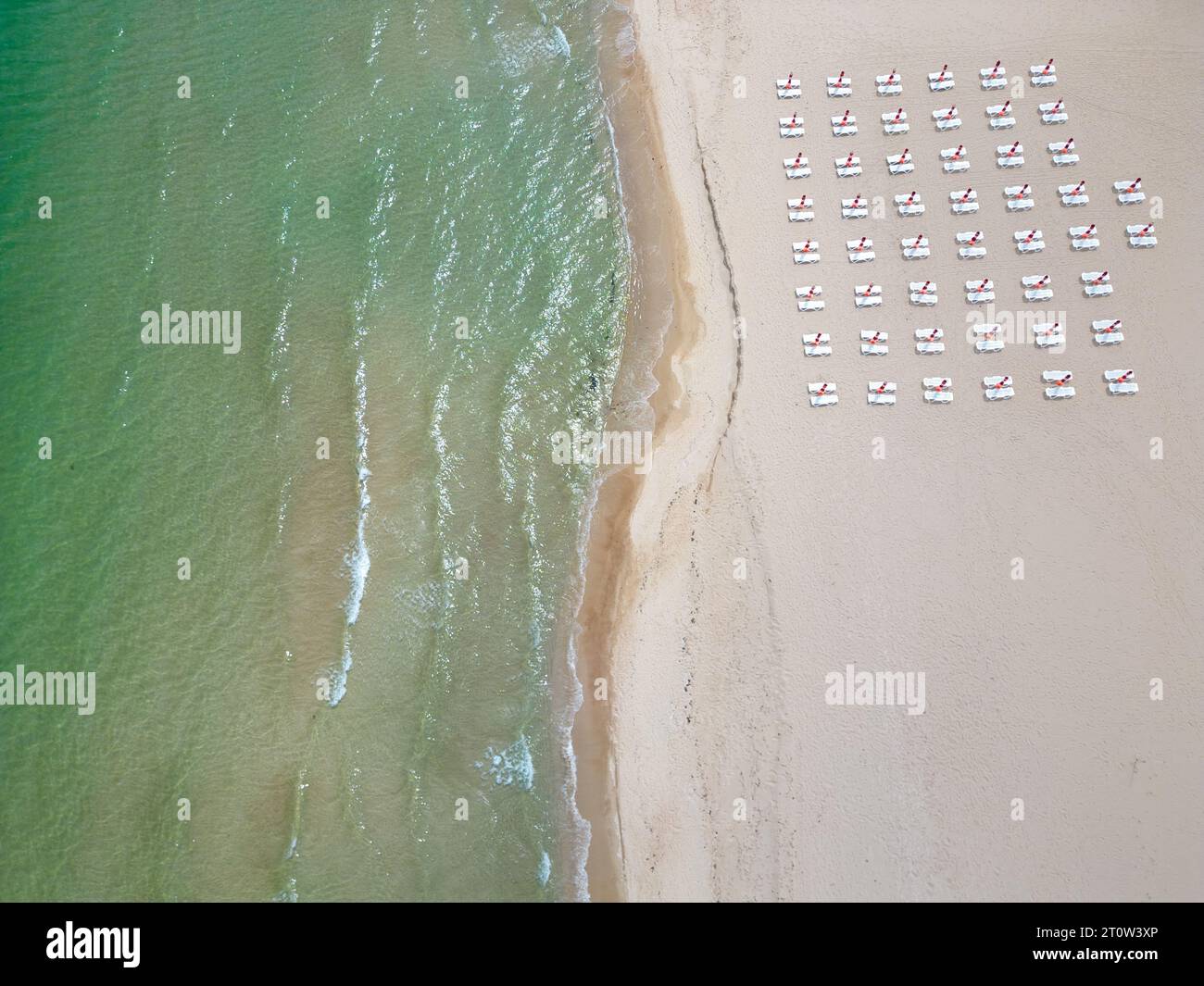 A sandy beach stretches along the seaside, adorned with empty sun ...