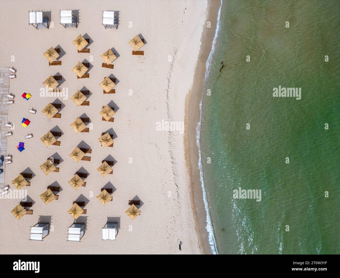 A sandy beach stretches along the seaside, adorned with empty sun ...