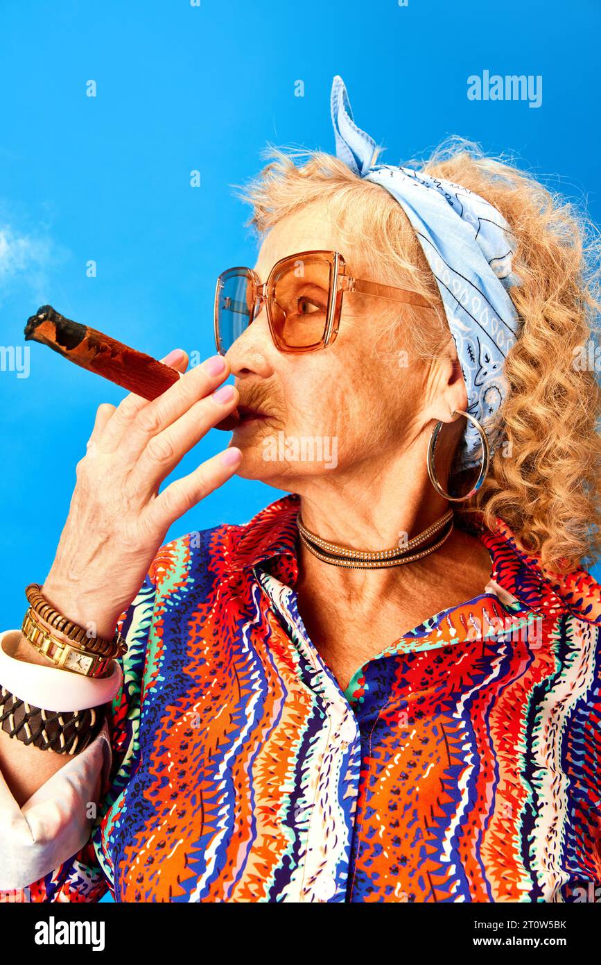 Portrait of senior woman in stylish accessories and sunglasses smoking ...