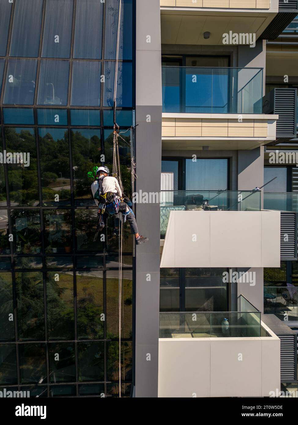 Industrial climber performs tasks at a great height on a glass wall of ...