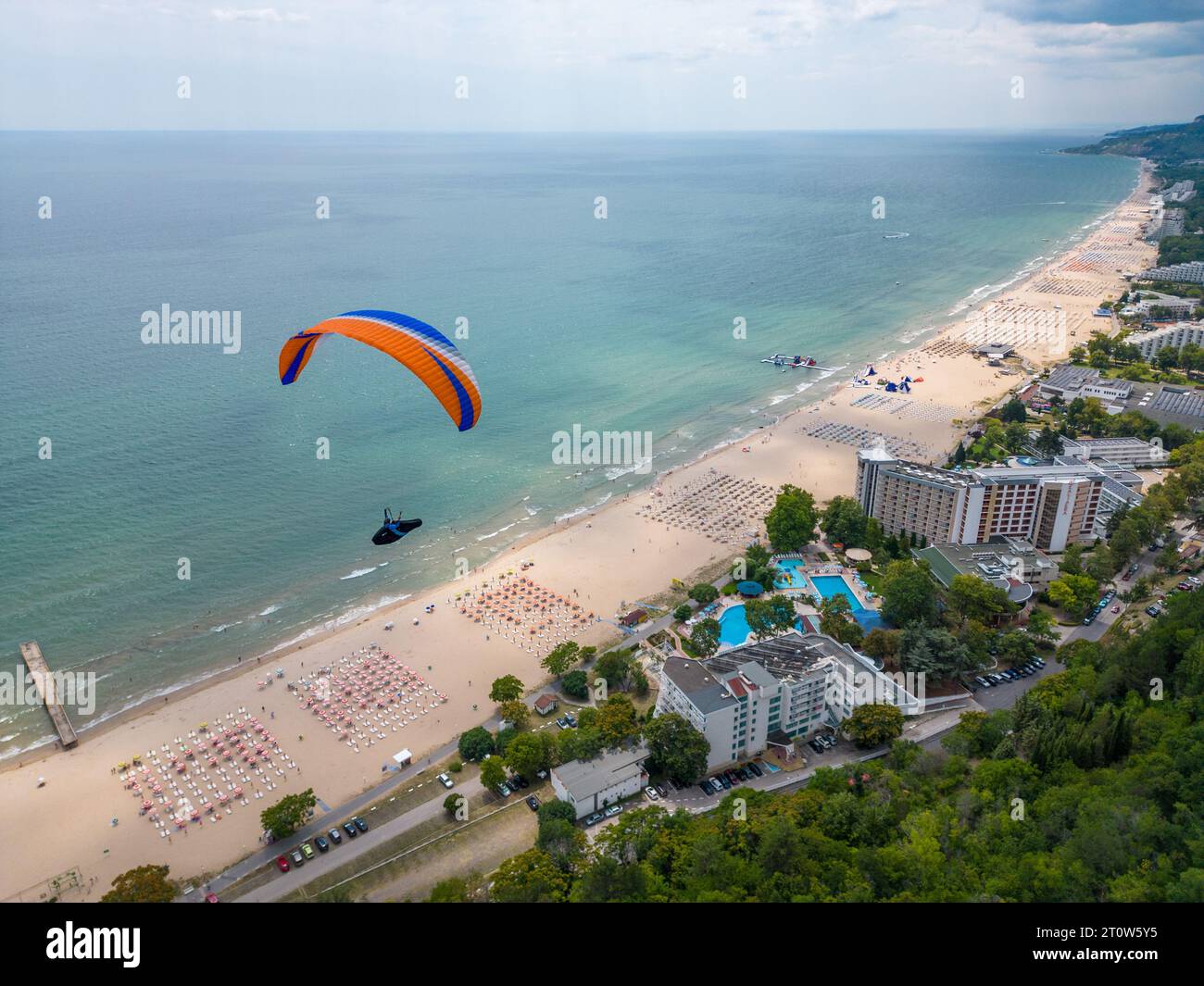 A paraglider soars over the sea and forest with a breathtaking view of ...