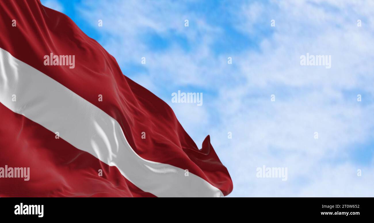 Republic of Latvia national flag waving in the wind on a clear day. Red field with a white ...