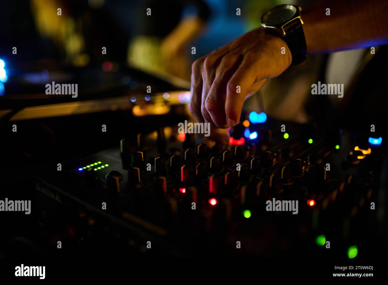 A close-up of the DJ's hand on the mixer console in a nightclub ...