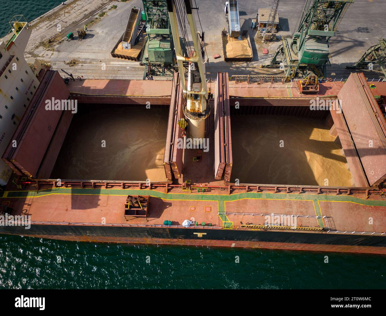 aerial close-up view of a bustling seaport, where a massive cargo ship ...