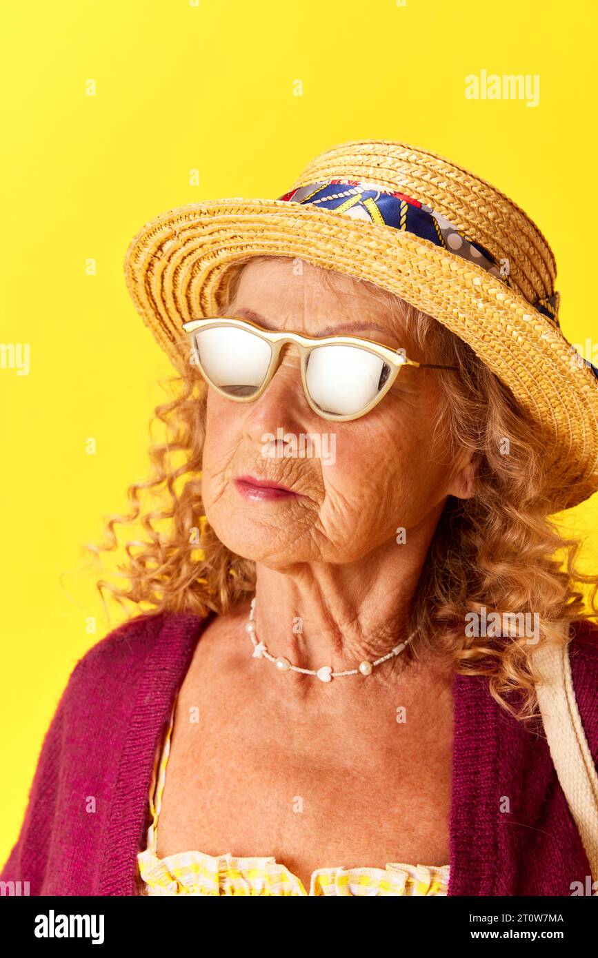 Portrait of beautiful senior woman in stylish straw hat and sunglasses ...
