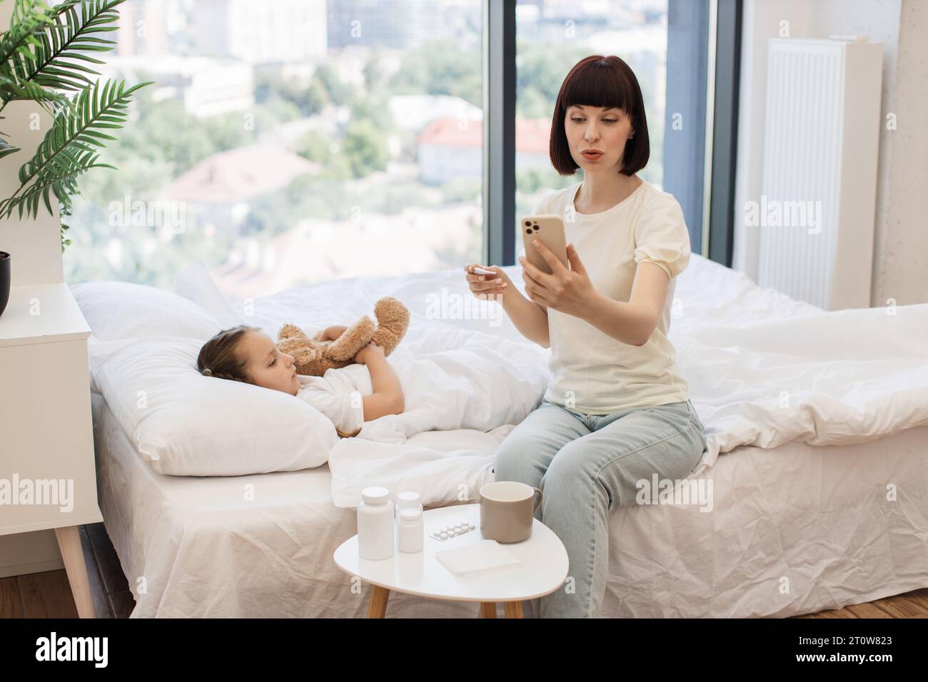Mother having video call with doctor while treating ill kid Stock Photo ...