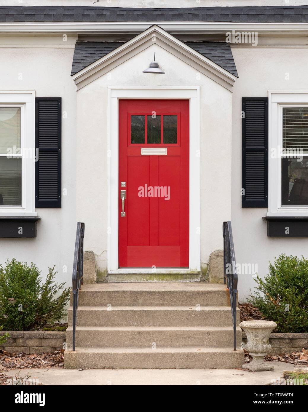 A red front door detail on a white home with concrete steps and iron ...