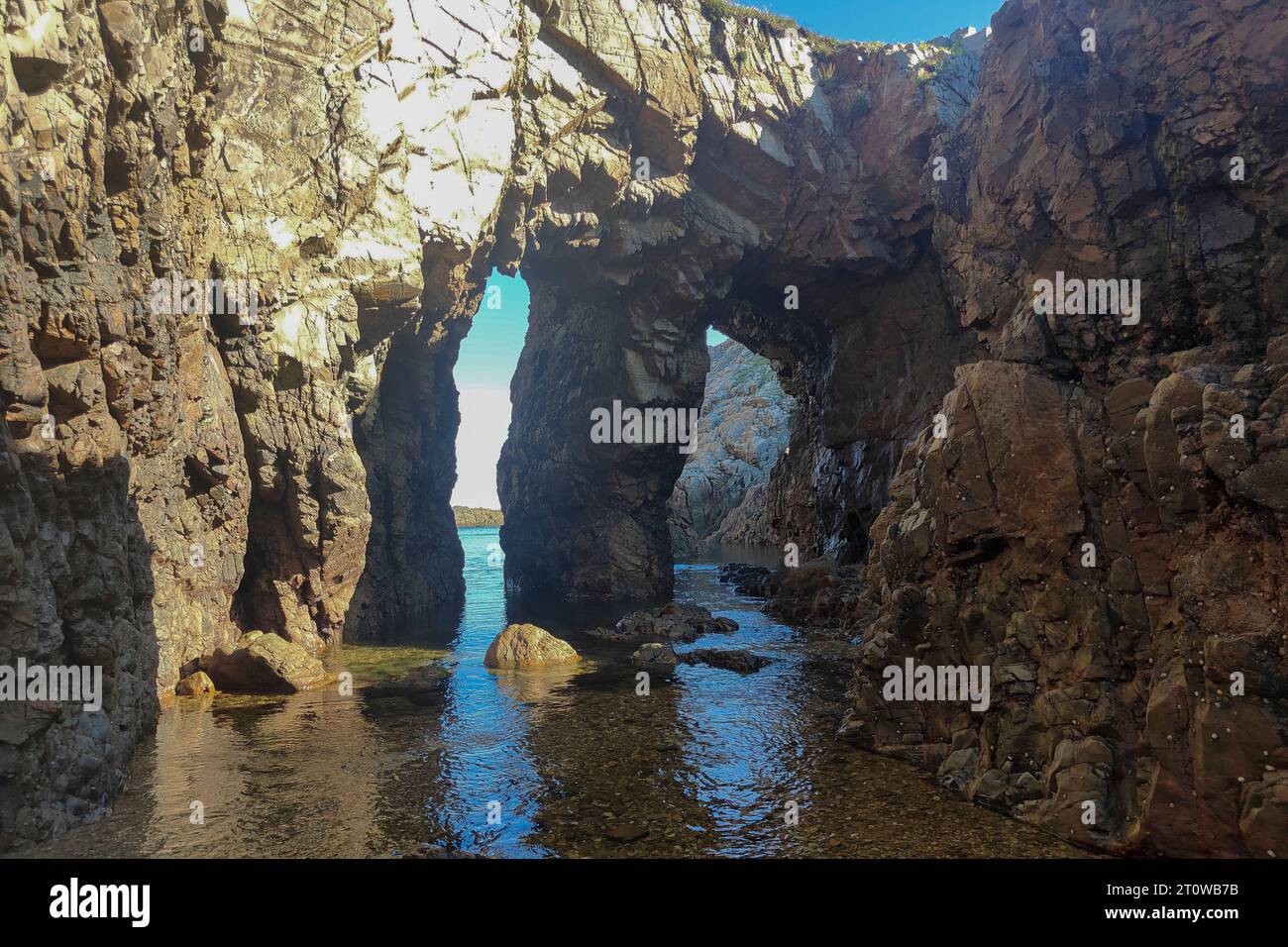 Jagged Rocks Forming a Majestic Arch in Clear Waters Stock Photo - Alamy