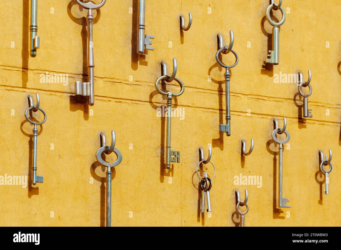 Various sizes and types of keys hanging on hooks on the yellow wall ...