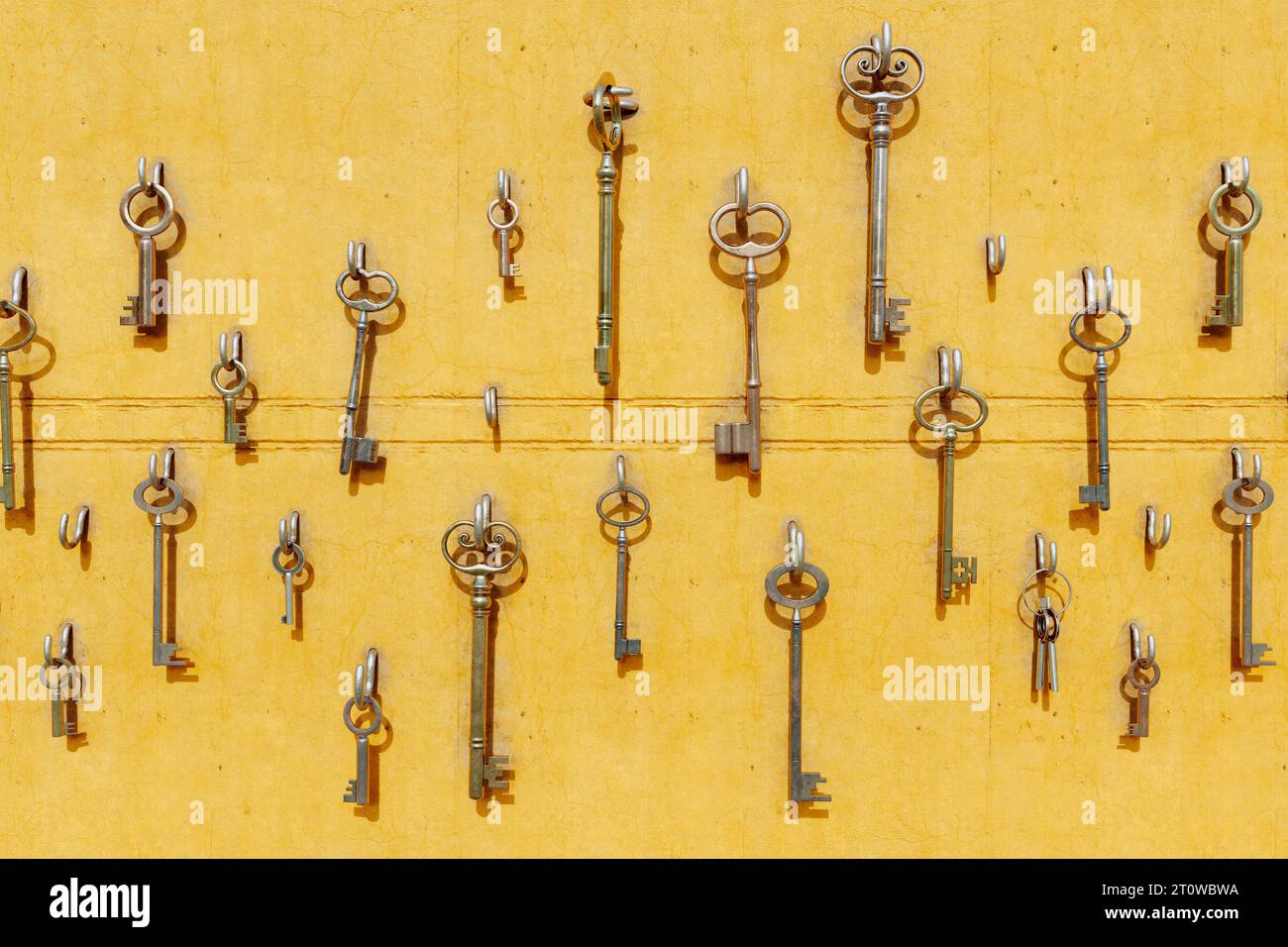 Various sizes and types of keys hanging on hooks on the yellow wall ...