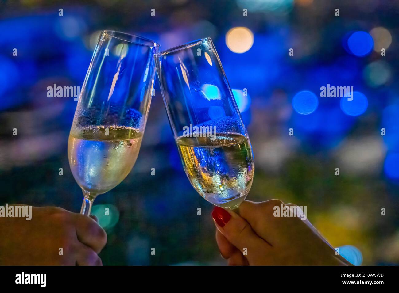 Two people toasting with glasses of champagne against the city view at ...