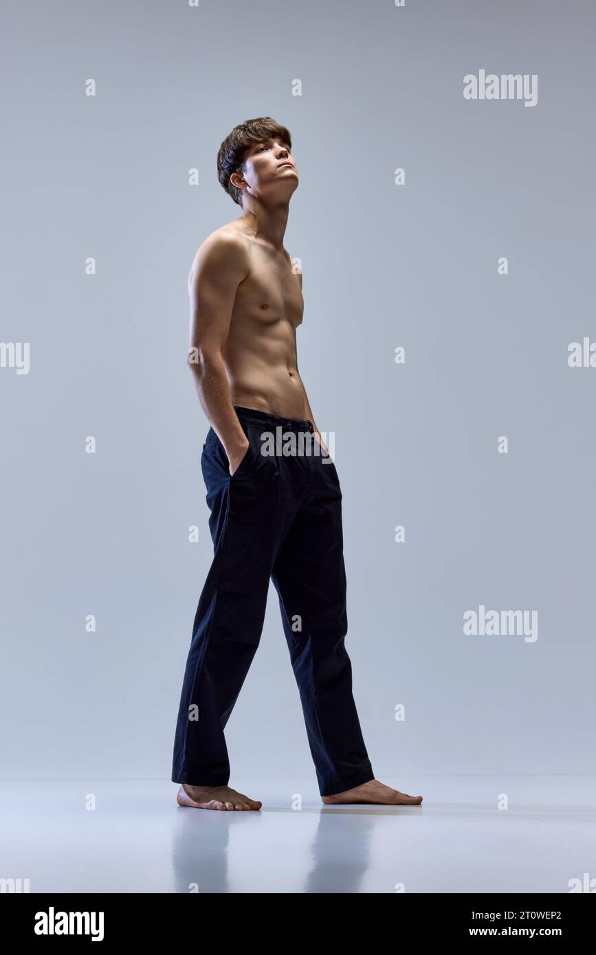 Full-length side view portrait of young man posing looking away in ...